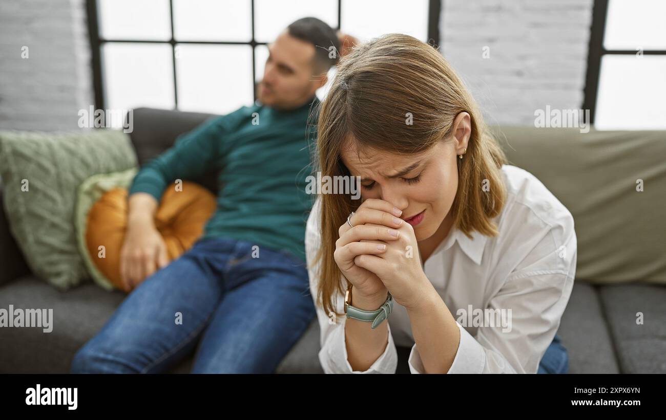 A crying woman and a concerned man sitting together in a home interior ...