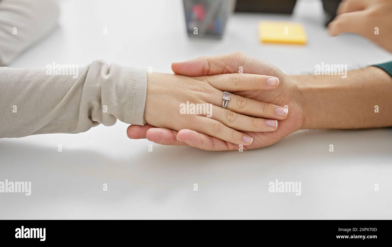 A man and woman, likely coworkers, engage in a handshake over an office ...