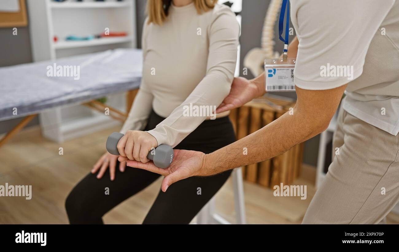 A woman in physiotherapy exercises her arm with a dumbbell assisted by ...