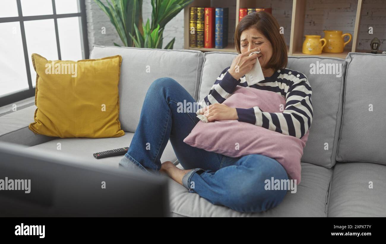 Mature hispanic woman crying at home on a couch, holding a tissue, with ...