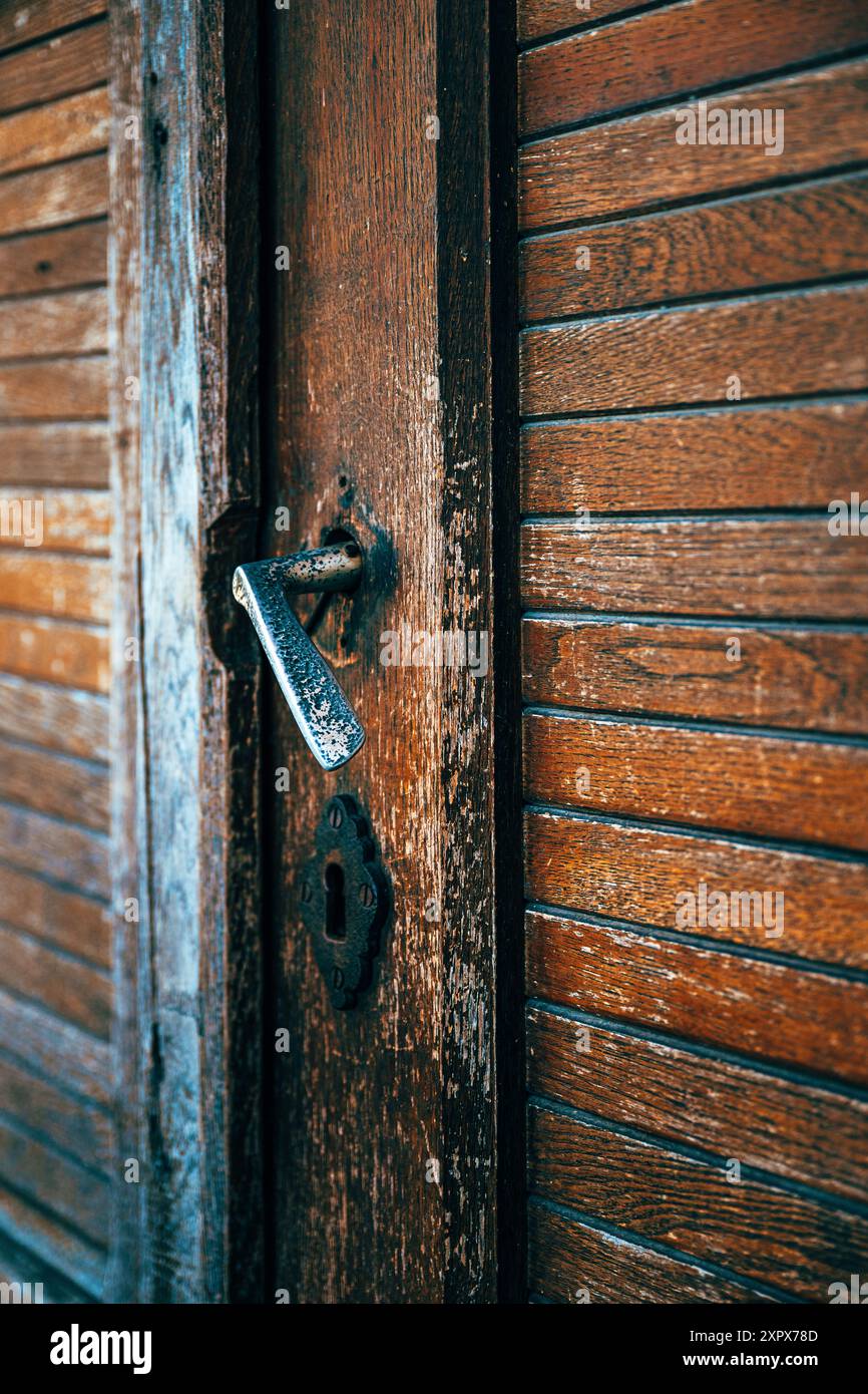 Old brown wooden door with worn handle and keyhole, selective focus ...