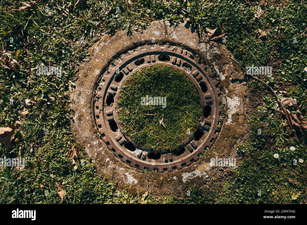 Old rusty manhole covered with grass, top view Stock Photo - Alamy