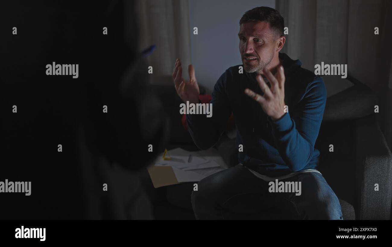 A worried man gestures during an intense interrogation by an unseen ...