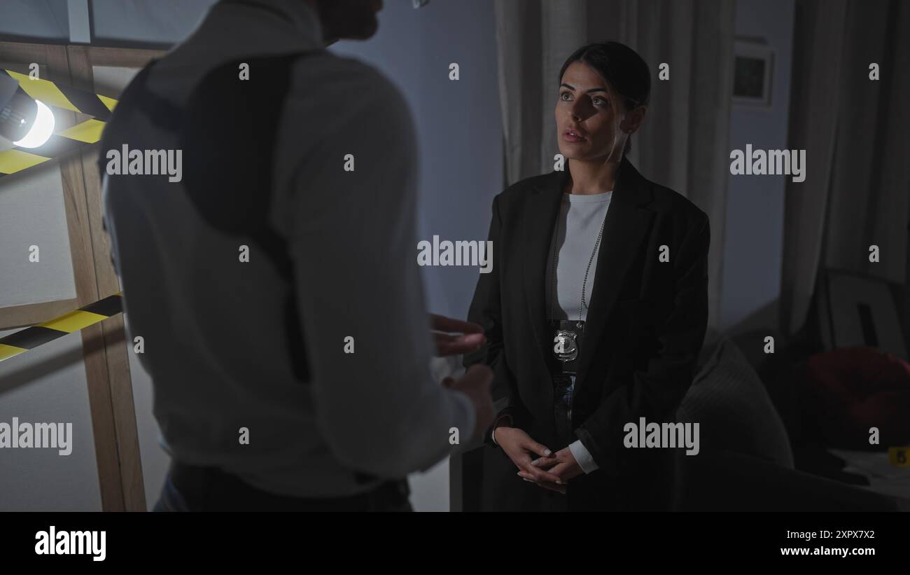 A man and a woman police officers investigate a dimly lit indoor crime ...