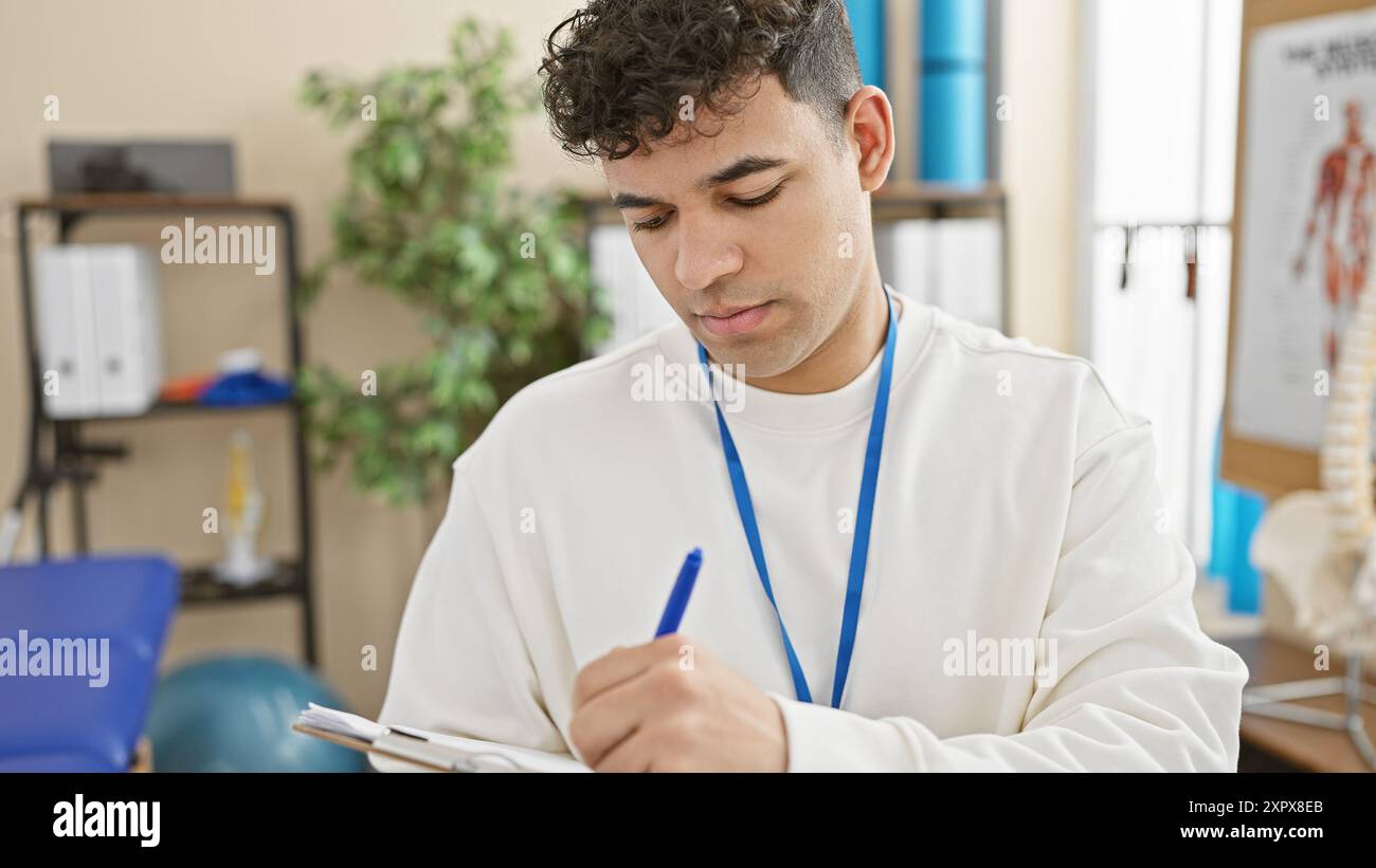 A young man working in a physiotherapy clinic, writing notes with a ...