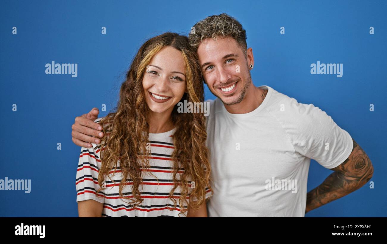A smiling couple embraces against a blue background, exemplifying a ...