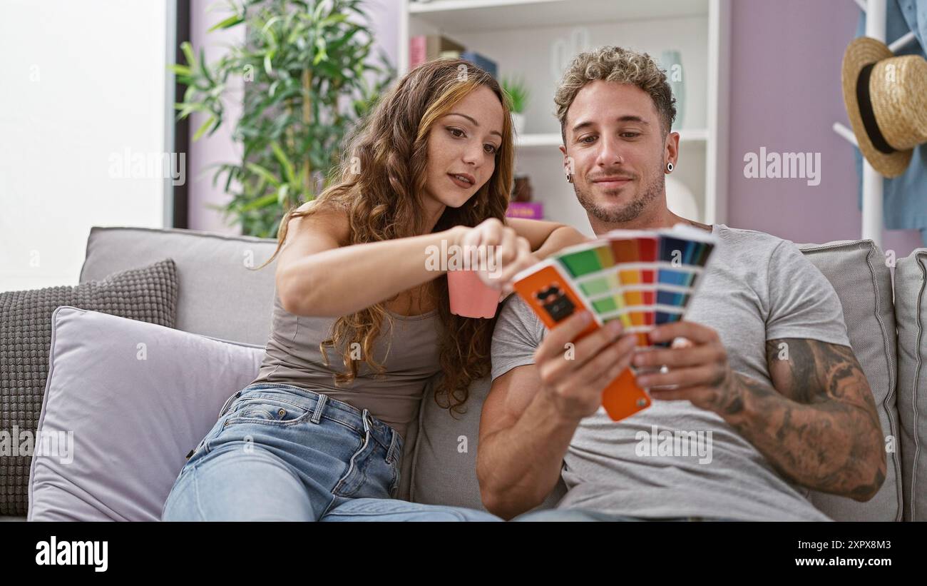 A woman and a man sitting on a sofa indoors comparing color swatches ...