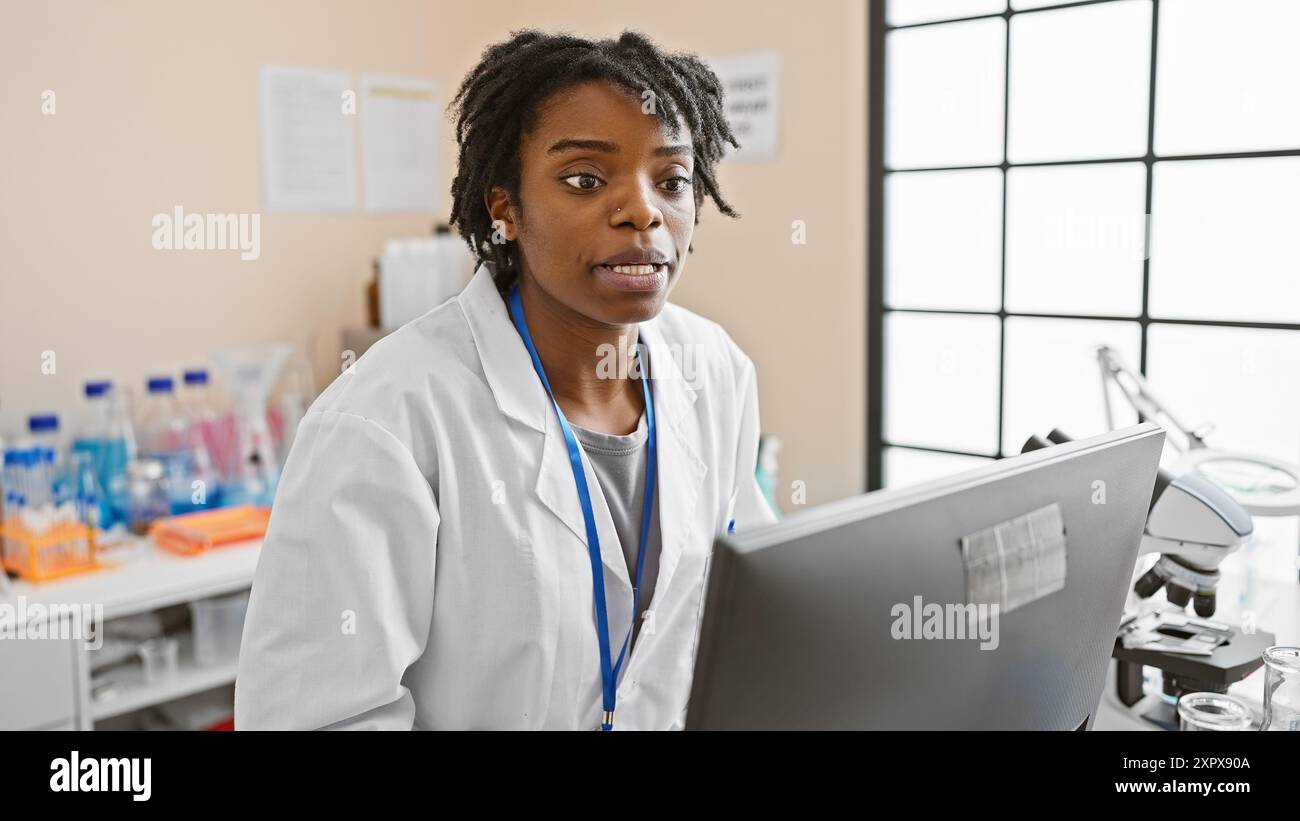 African american woman scientist with dreadlocks using a computer in a ...