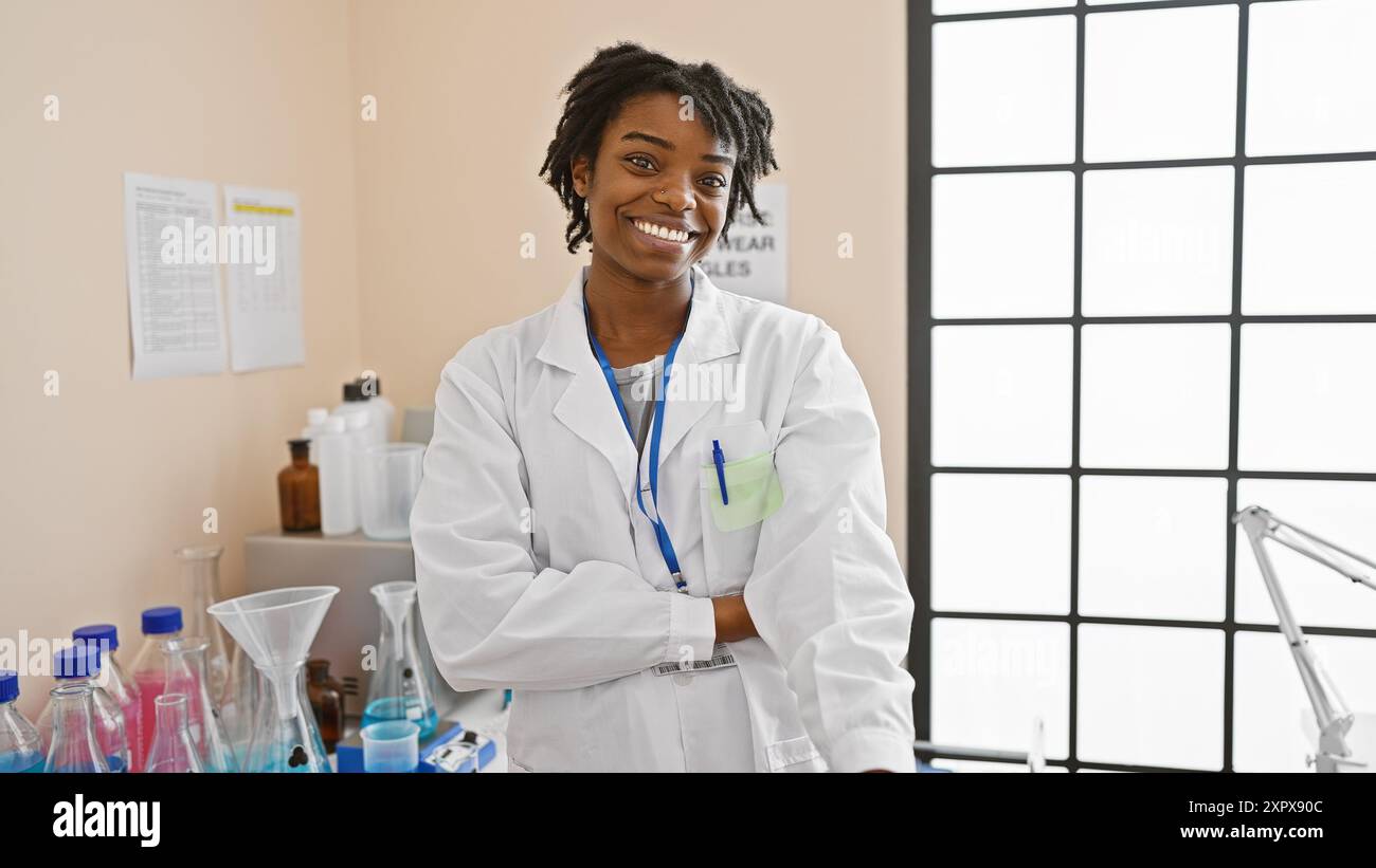 Smiling young black woman with dreadlocks, dressed as a scientist ...