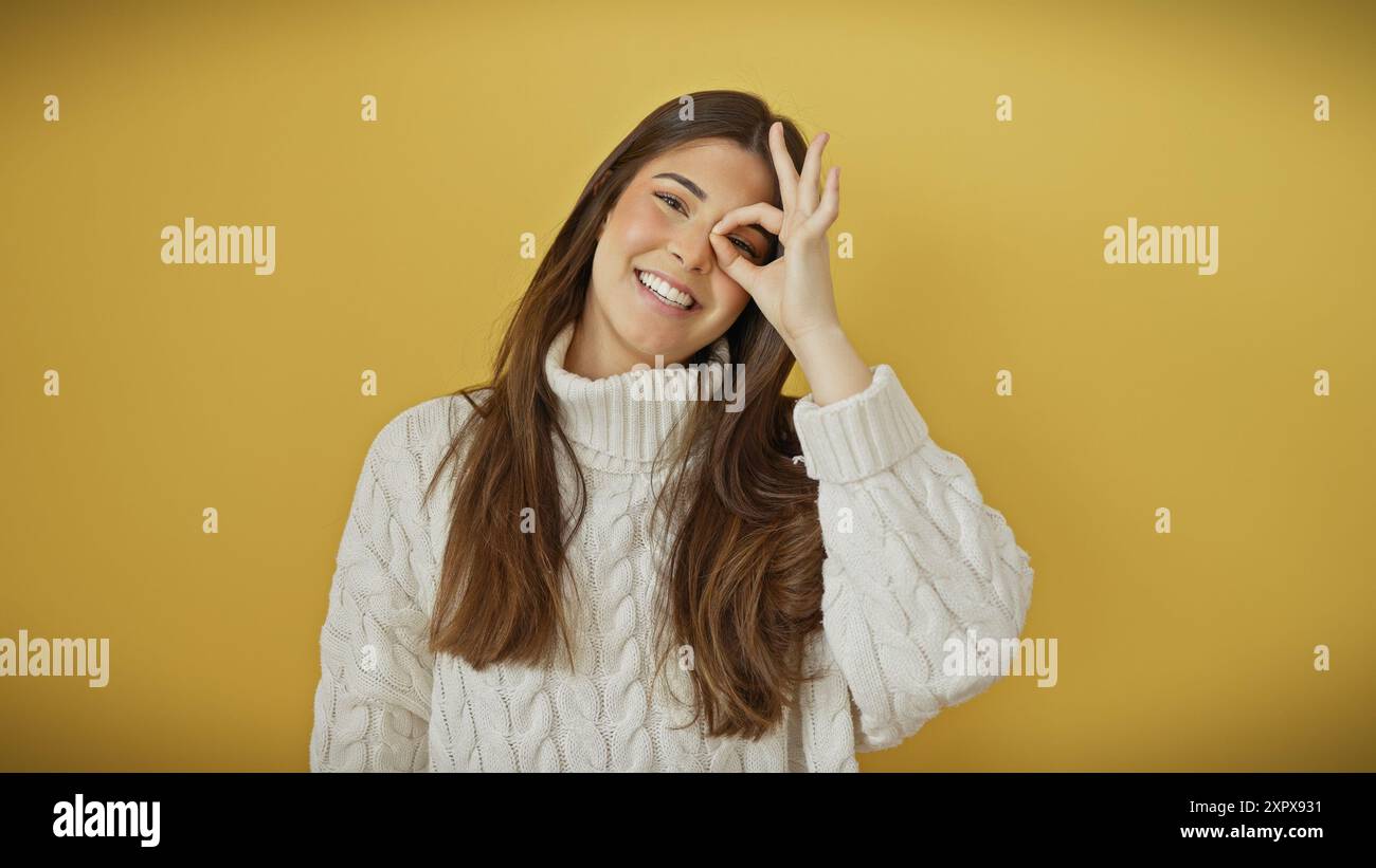 A joyful young woman makes an okay gesture with her hand against a ...