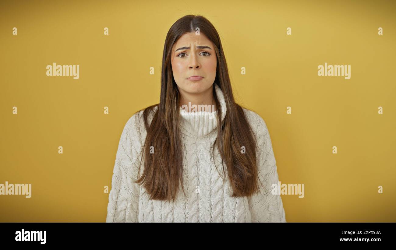A perplexed young hispanic woman stands against an isolated yellow ...