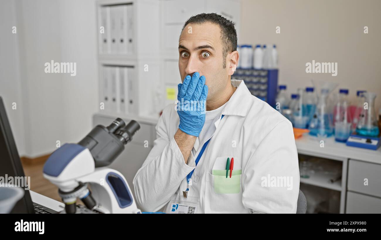 Surprised hispanic man in lab coat and gloves working in a laboratory ...