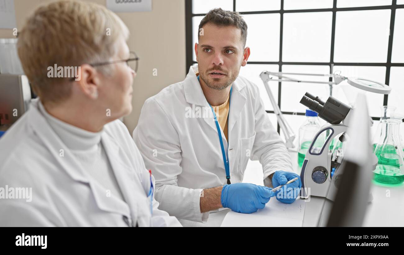 Two scientists, a man and a woman, collaborate in a laboratory ...