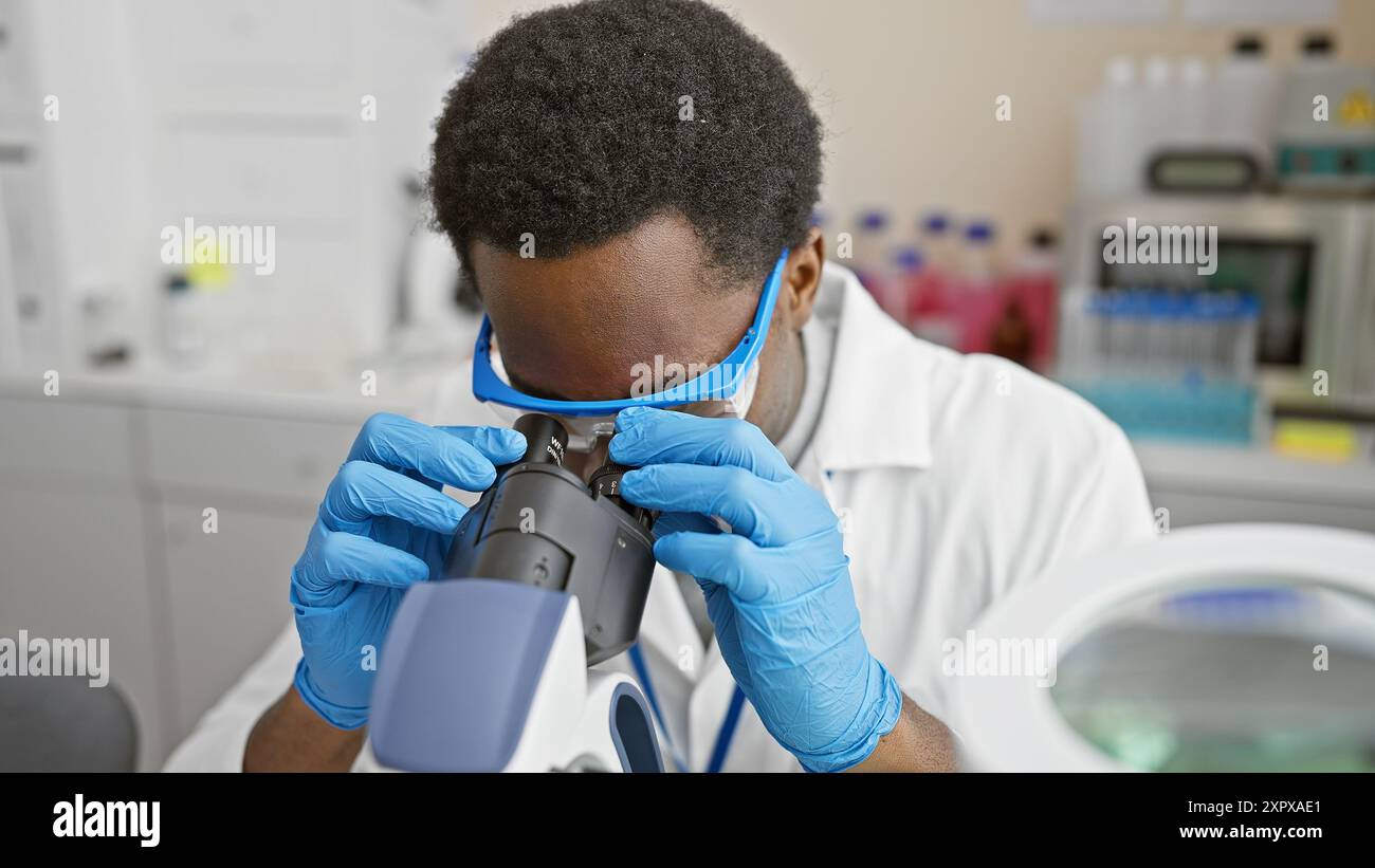 African american male scientist using microscope in laboratory setting ...