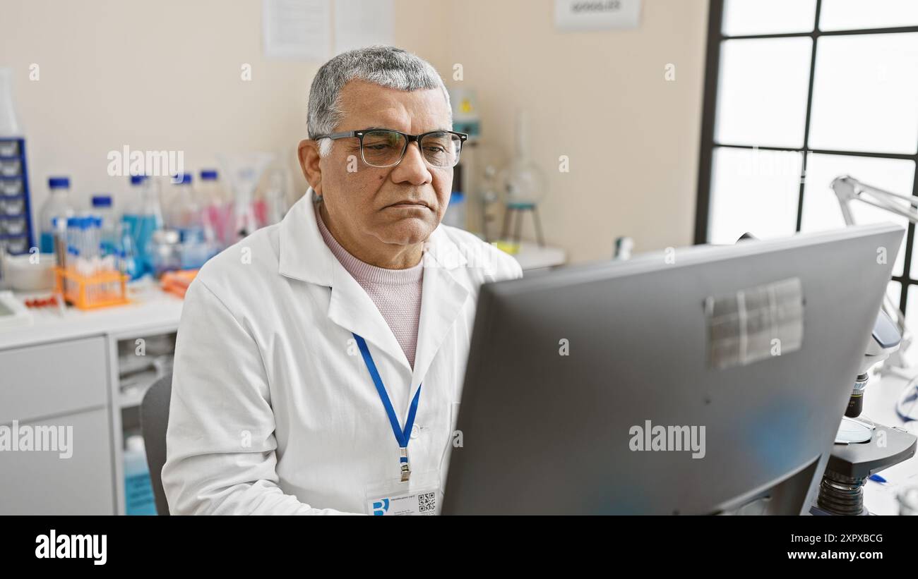 Middle-aged man in lab coat works at computer in clinical laboratory ...