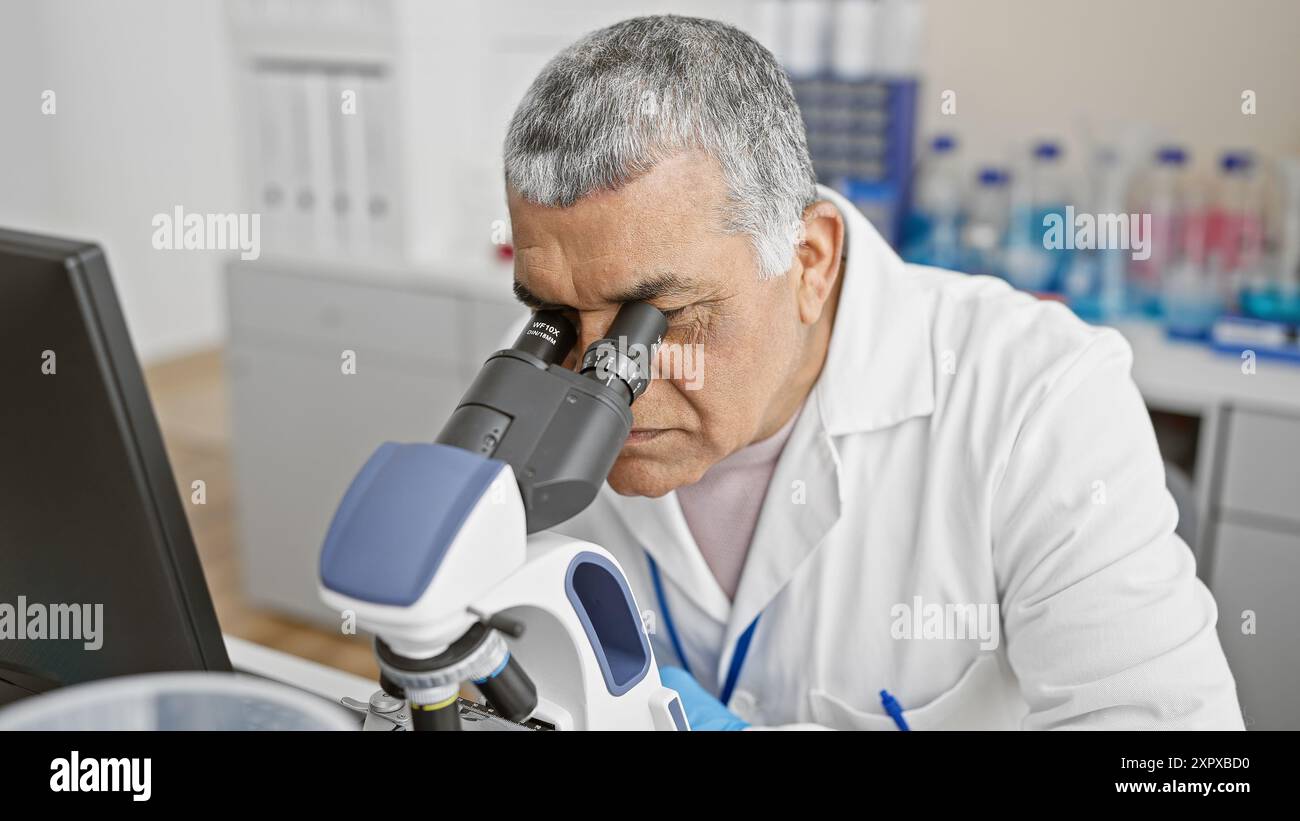 A senior man scientist analyzing samples using a microscope in a laboratory setting Stock Photo ...