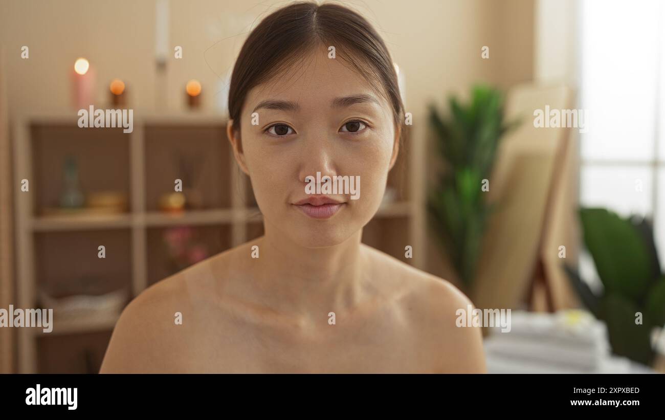 Beautiful young chinese woman at a spa center with candles and plants ...