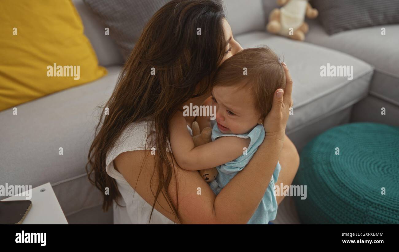Woman comforting crying toddler in cozy living room, representing family love and togetherness ...