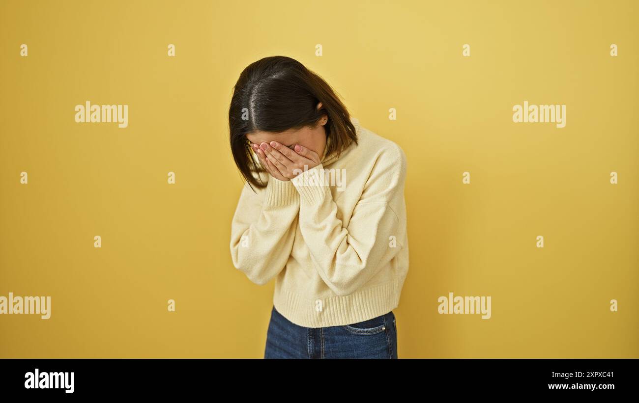 A distraught young hispanic woman covers her face with her hand against ...