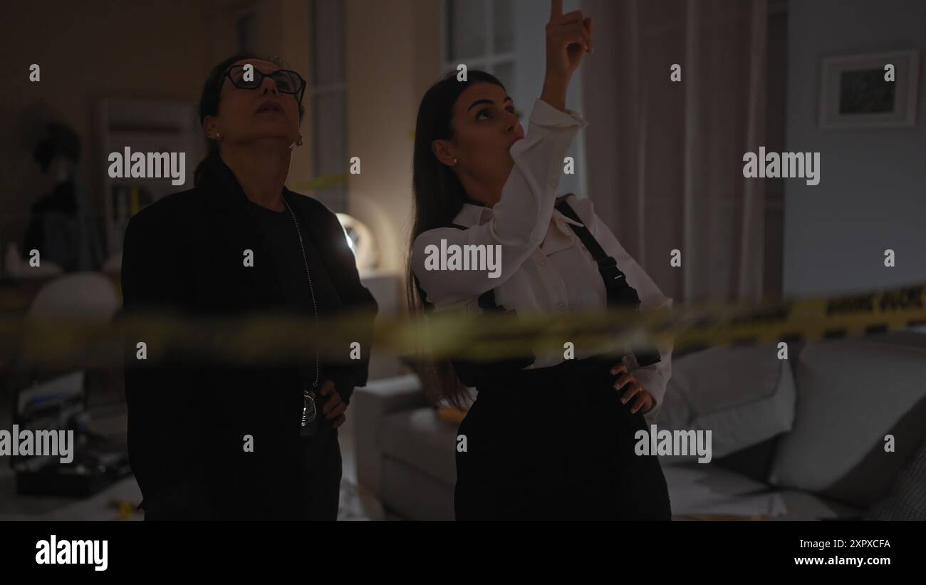 Two women detectives investigate a dark indoor crime scene, analyzing ...