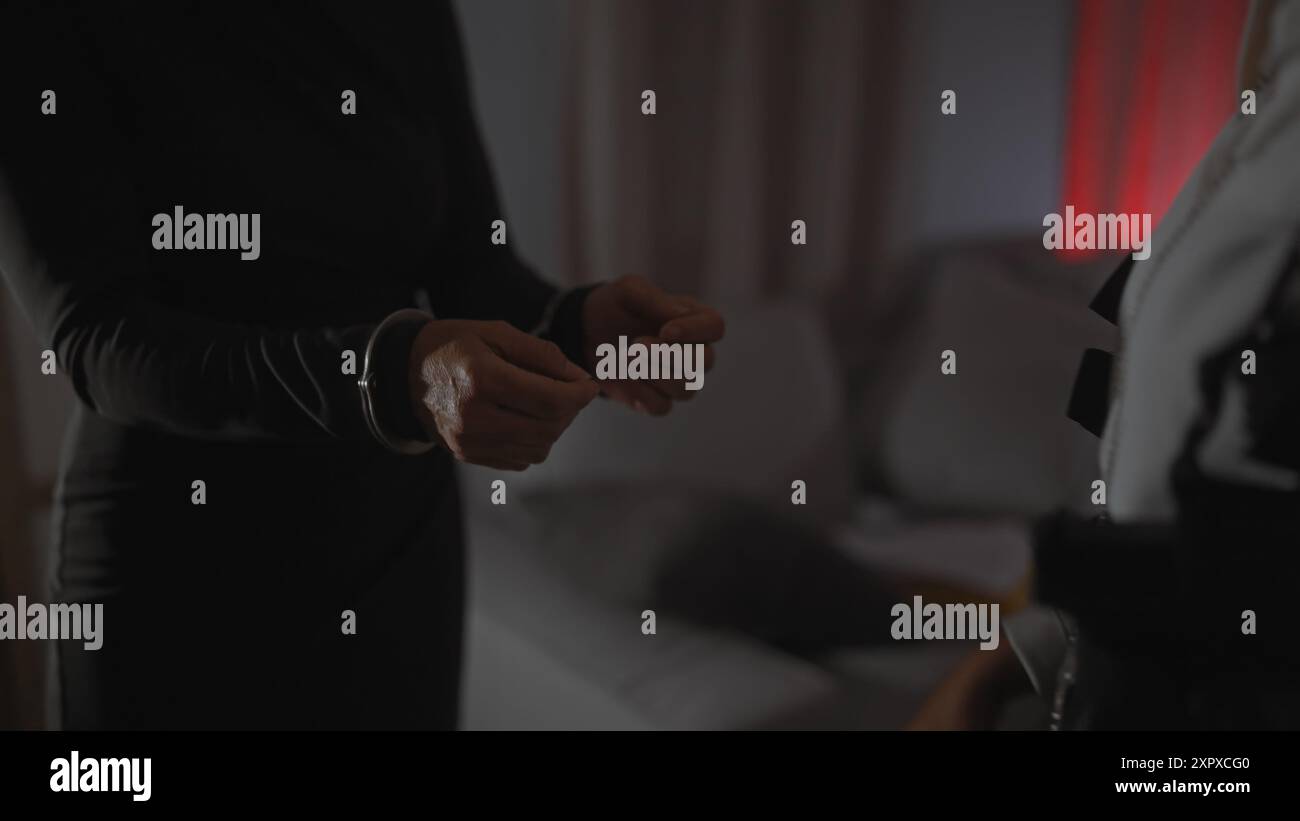 Two people in handcuffs in a dimly lit indoor setting implying a ...