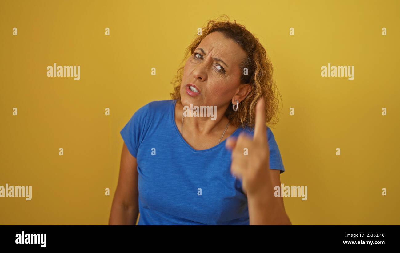 Mature hispanic woman with curly hair in a blue shirt pointing and ...
