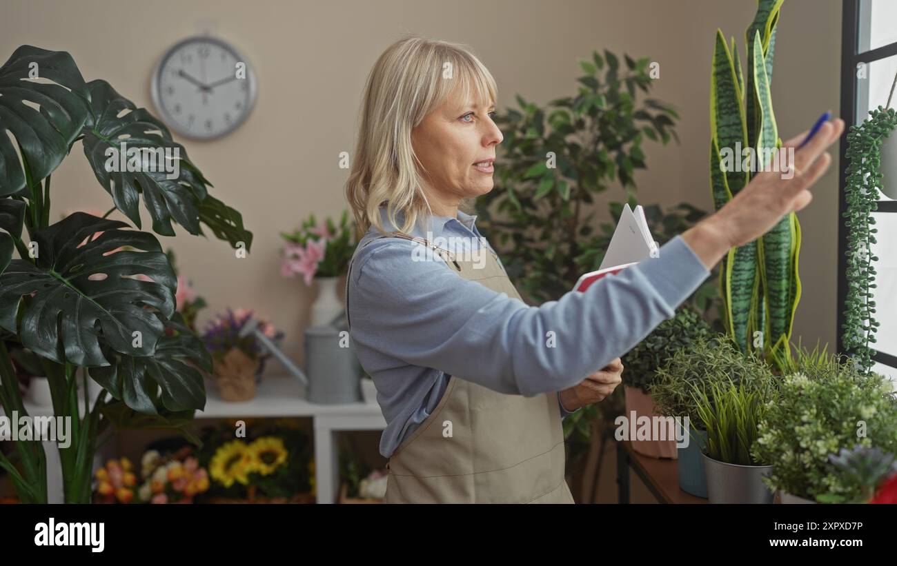 A mature blonde woman arranging plants in an indoor flower shop setting ...