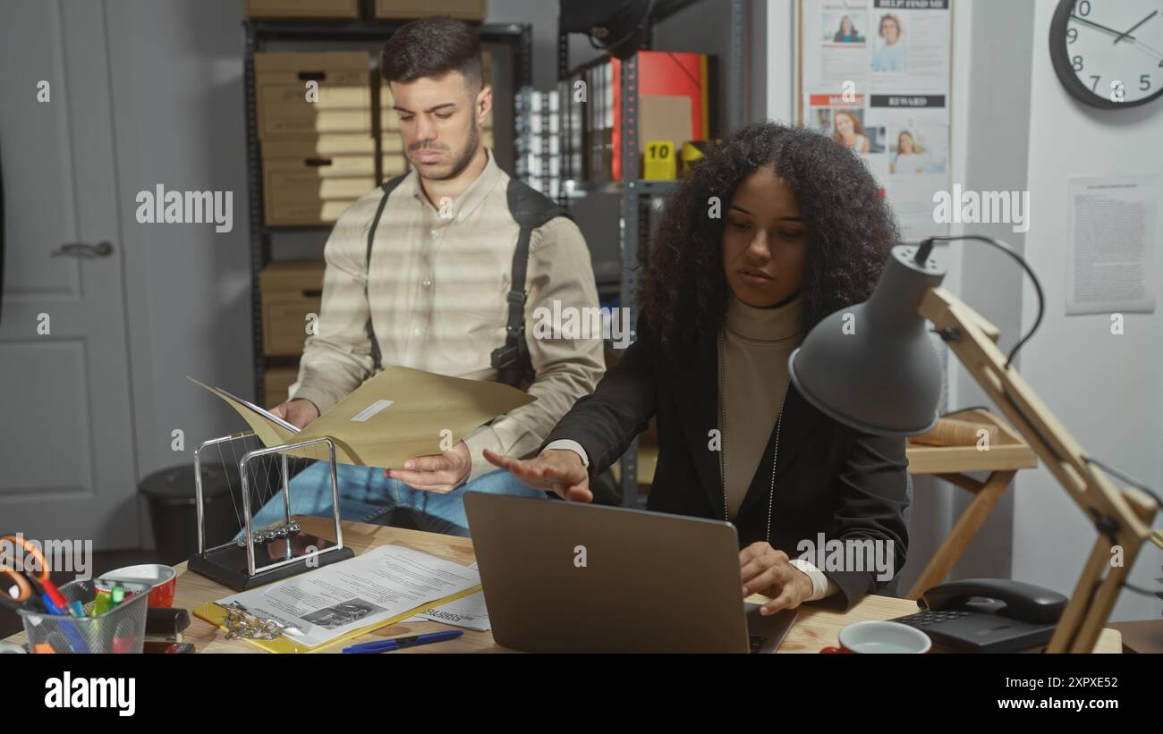 A man and woman detective team examines evidence at an office ...