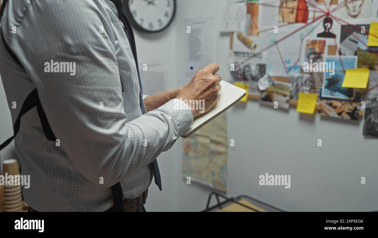 A mature man takes notes in a police station with a clue board full of ...