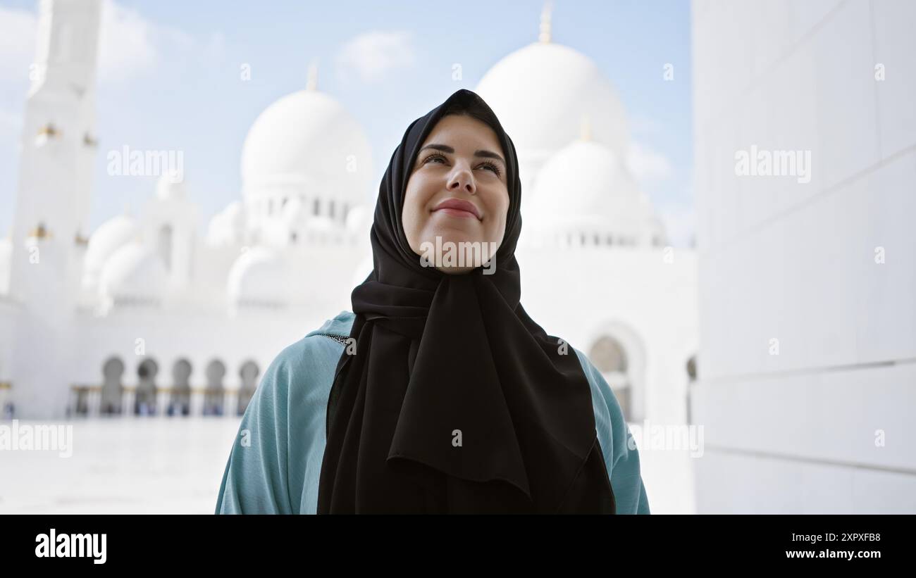 A smiling young woman wearing a hijab in front of abu dhabi's sheikh ...