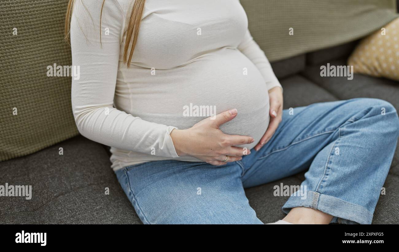A pregnant woman in casual attire is sitting comfortably indoors ...