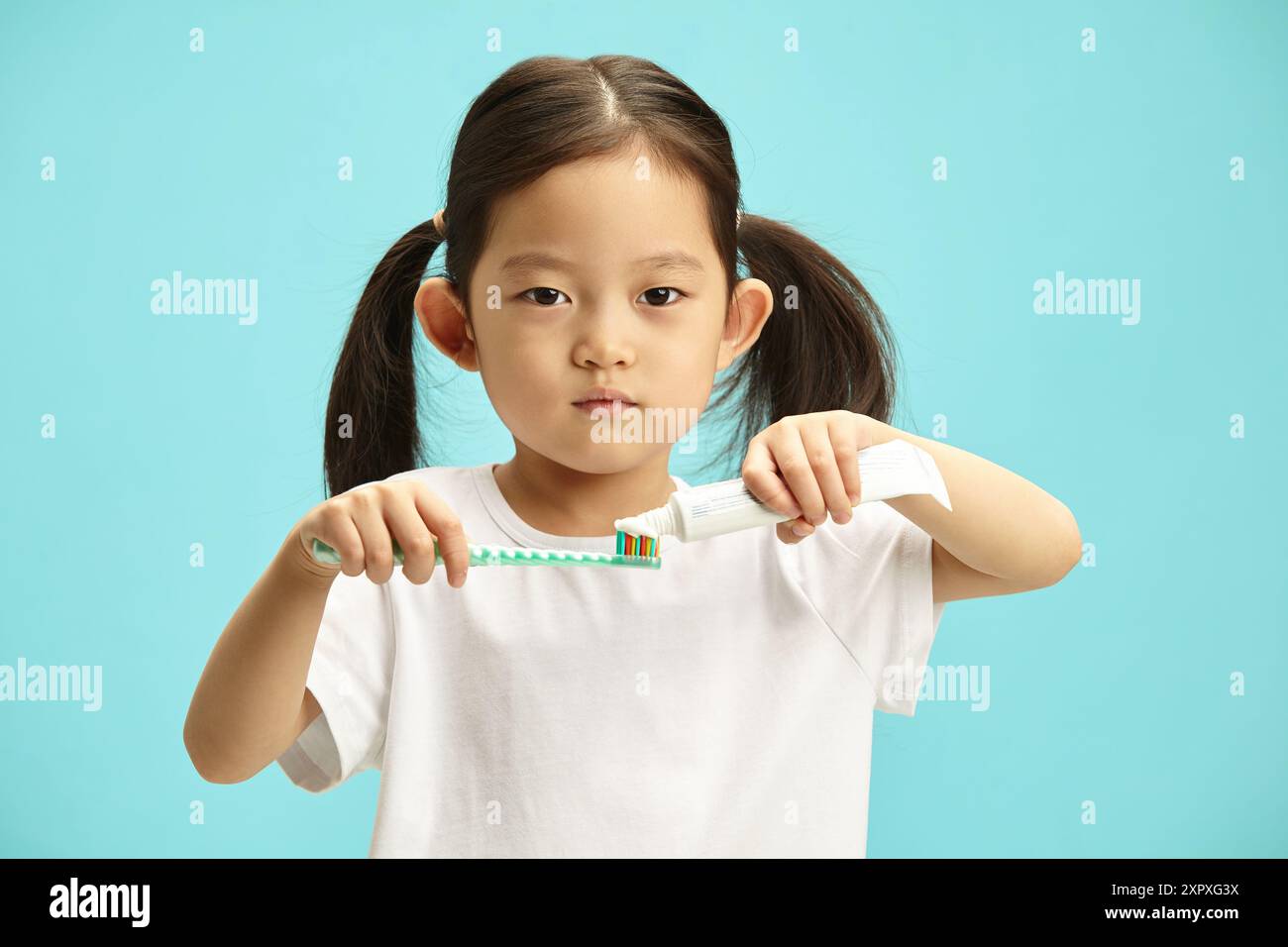 Japanese child girl squeeze toothpaste from tube on toothbrush and look ...