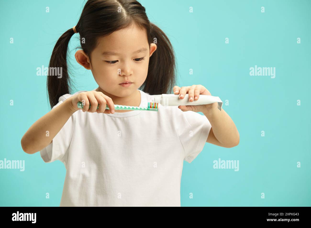 Asian ethnicity child squeeze toothpaste from tube on toothbrush ...