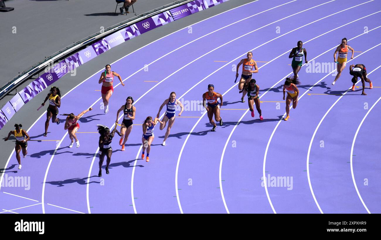 Runners exchange batons in a women's 4x100-meter relay heat at the 2024 ...