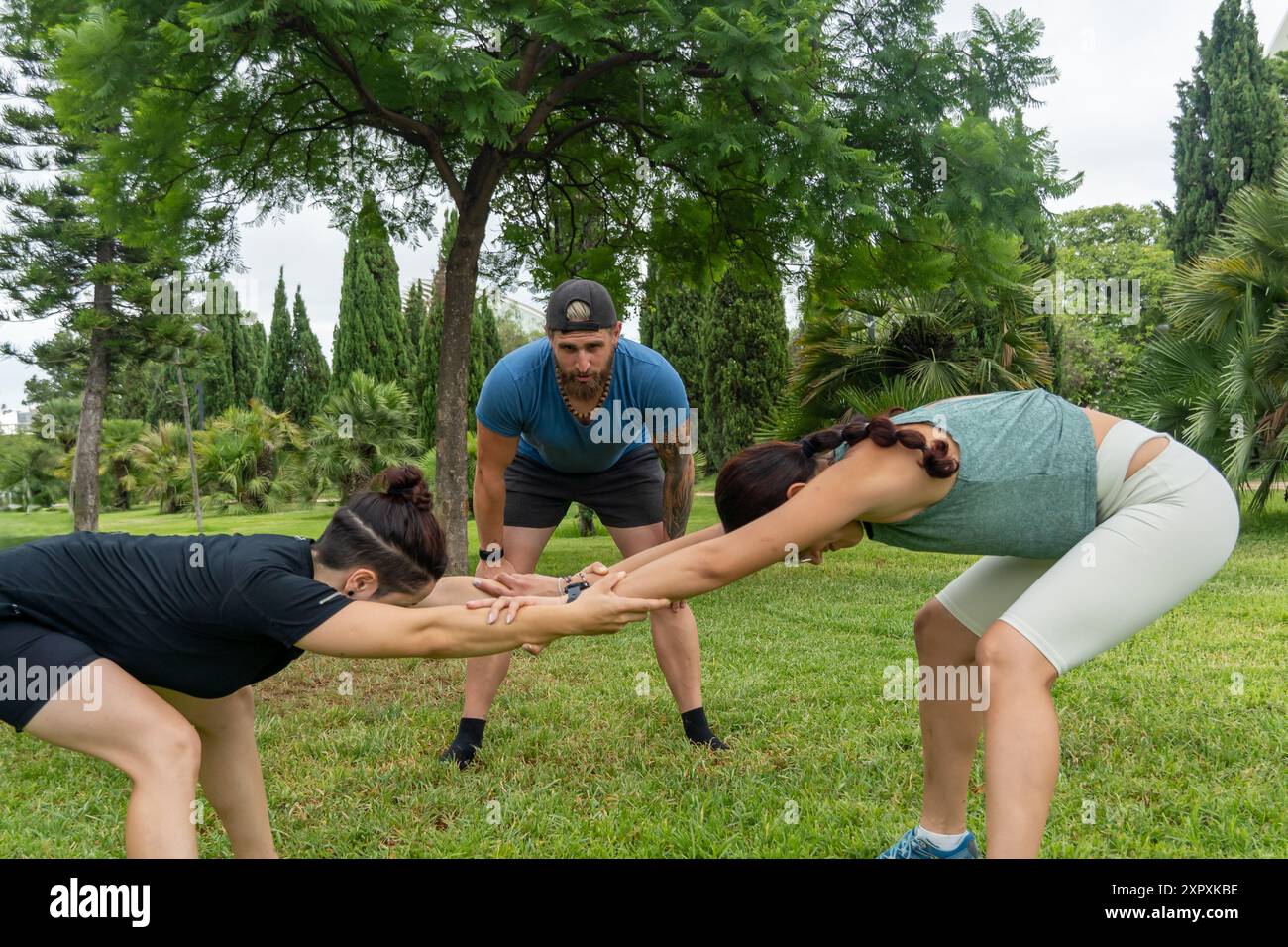 A personal trainer instructs two women in a stretching exercise during ...