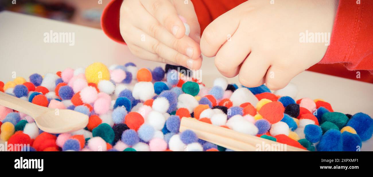 Preschooler playing with small colorful pompoms. Development of kids ...