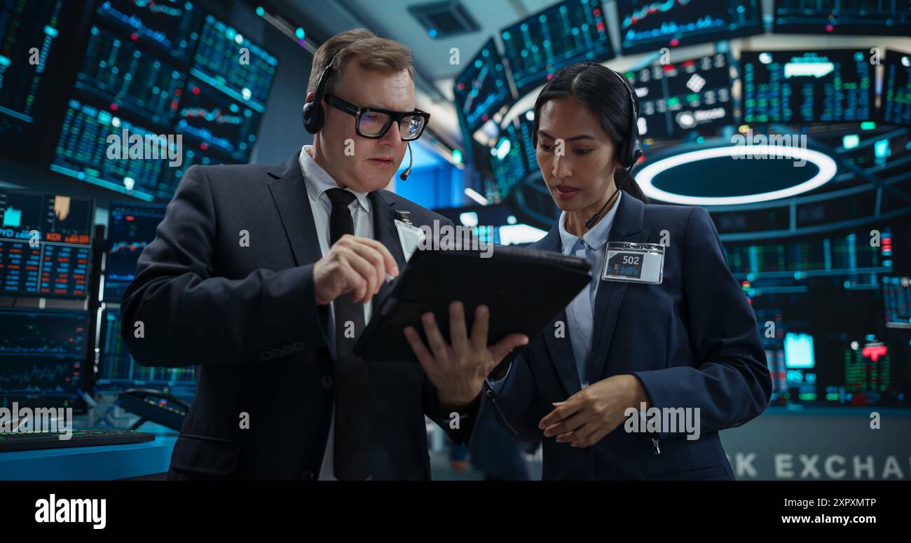 Team of Male and Female Stock Exchange Brokers Using Tablet Computer ...
