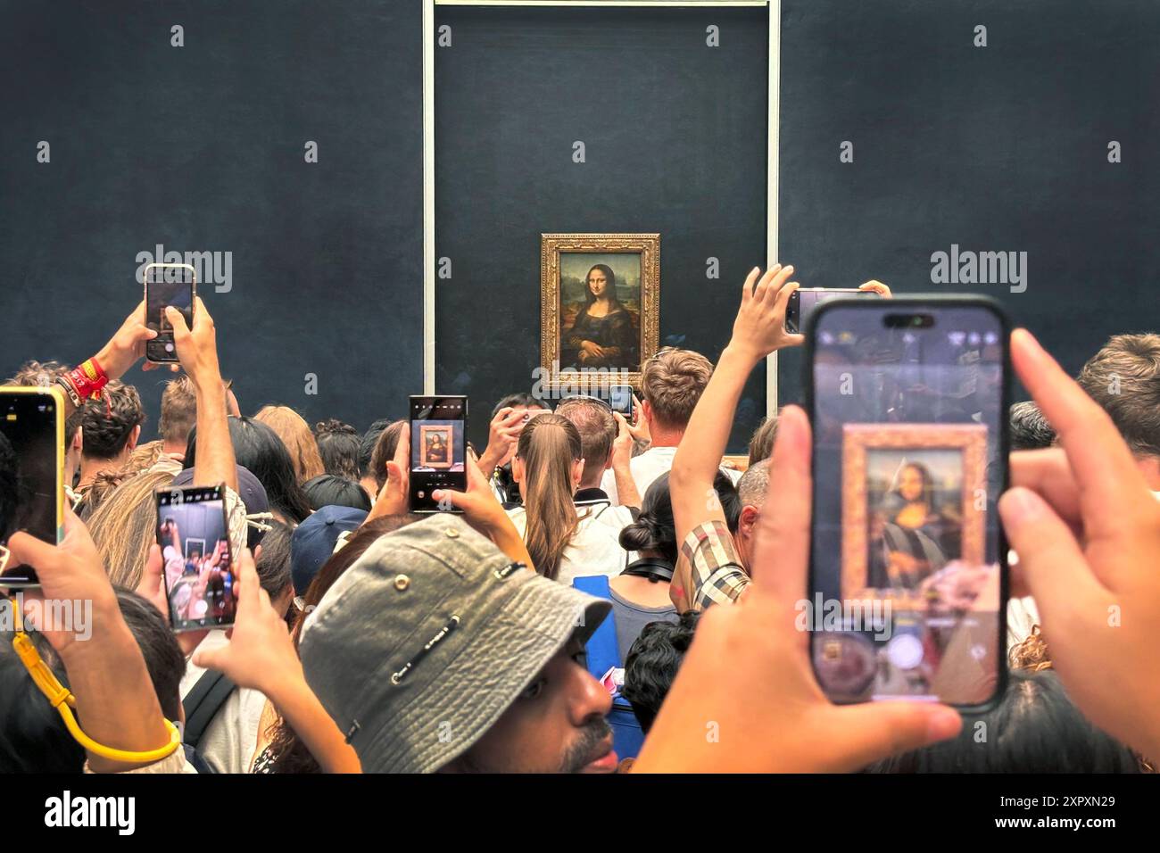 Tourists jostle each other to see and take a photograph of Leonardo da ...