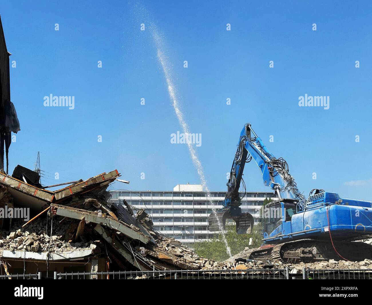 Demolition of building with excavator under blue sky Stock Photo - Alamy