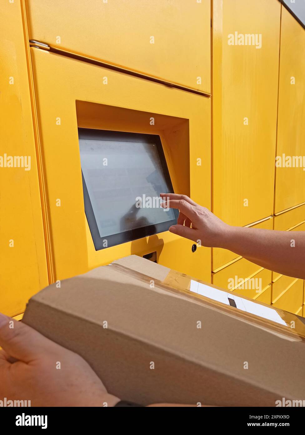 A woman with a package in her arms enters the pickup information on the ...