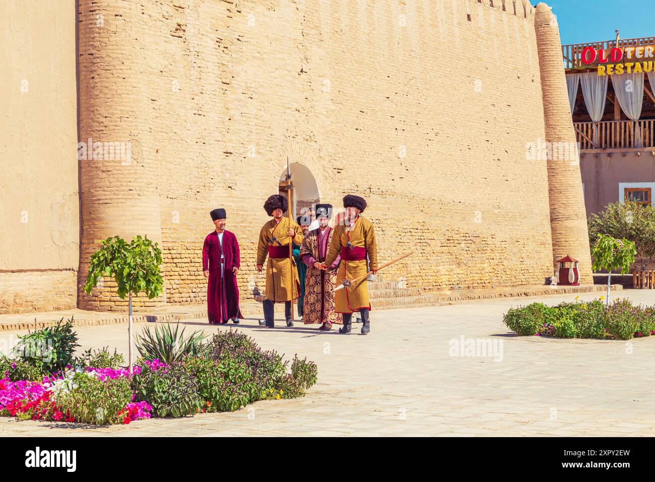 People in traditional Uzbek clothing at the fortress wall of the ...