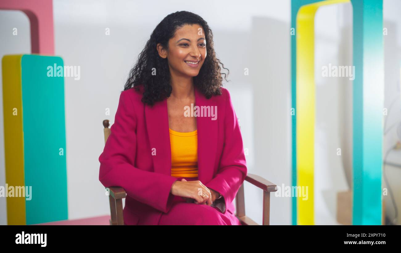 Young Black Female Host In Vibrant Pink Suit And Yellow Top, Smiling ...