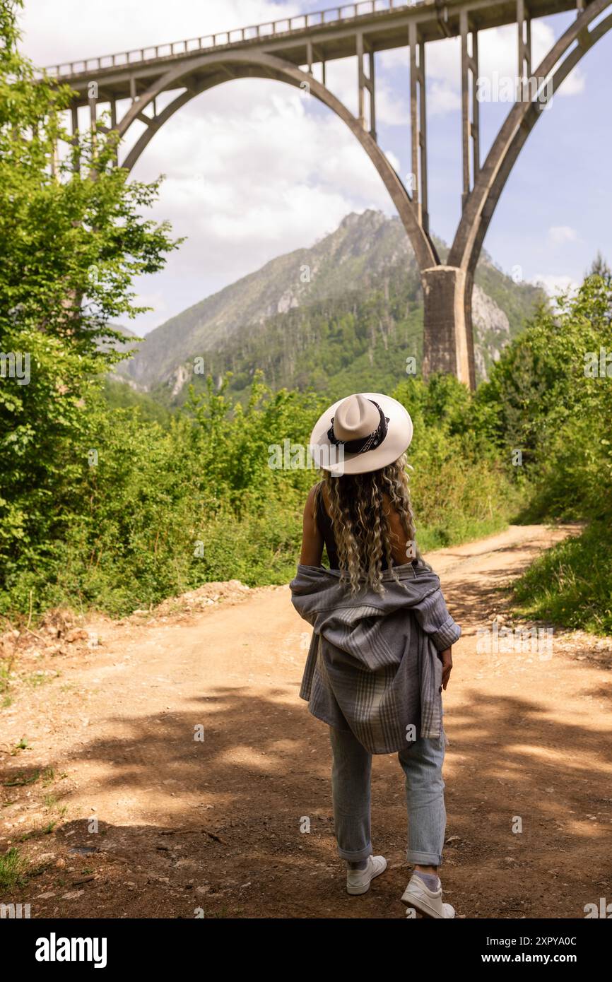 A girl in a hat stands against the backdrop of a beautiful arched ...
