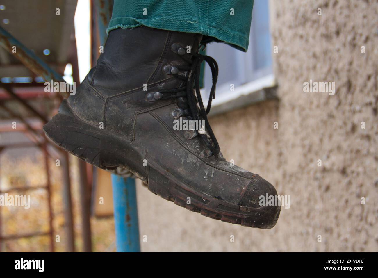 Close-up of the leg of a construction worker sitting on scaffolding and ...