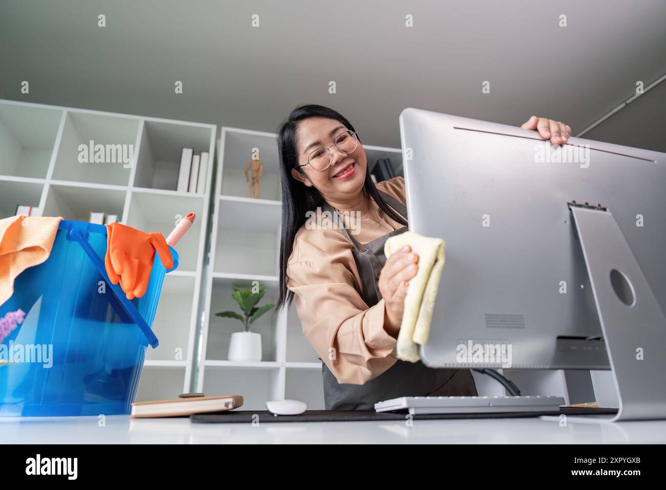 Cheerful Maid Housekeeper Cleaning Office Desk and Computer Monitor in ...