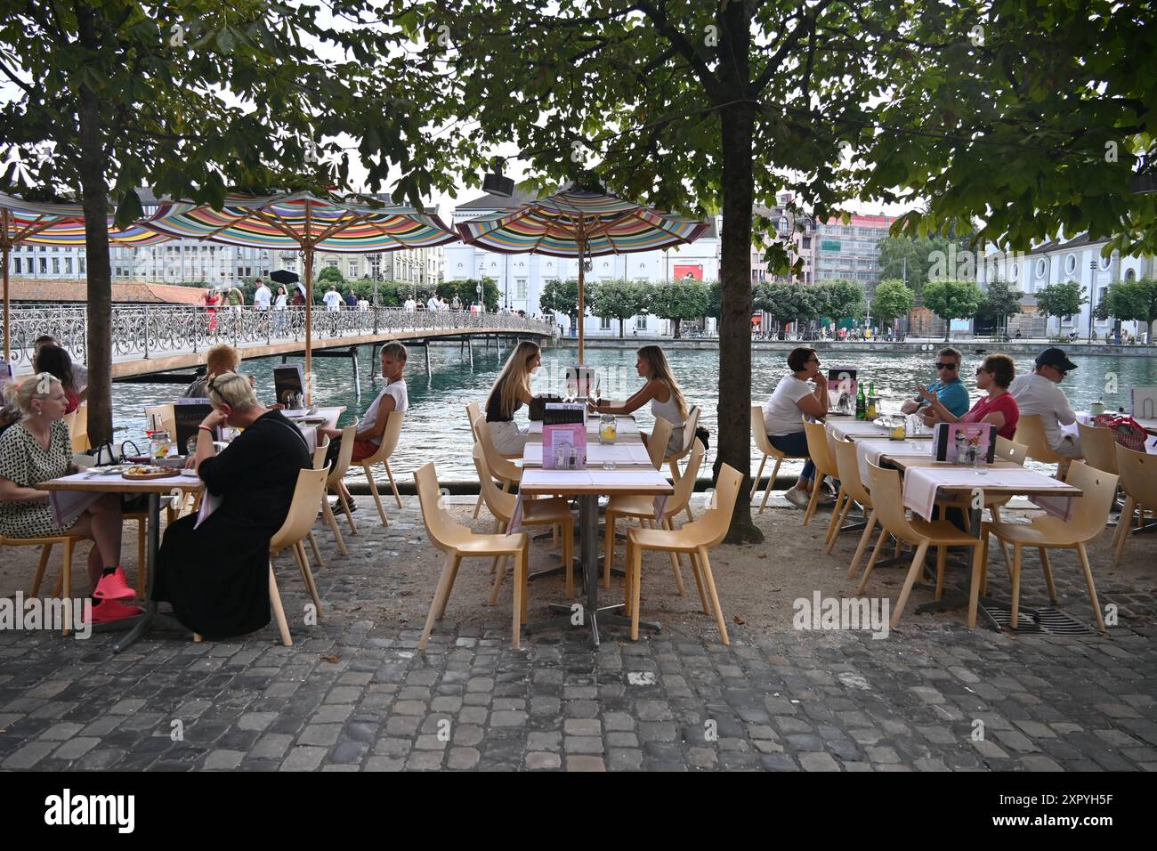 Tourists sitting outdoor in a bar facing river Reuss in Lucerne ...