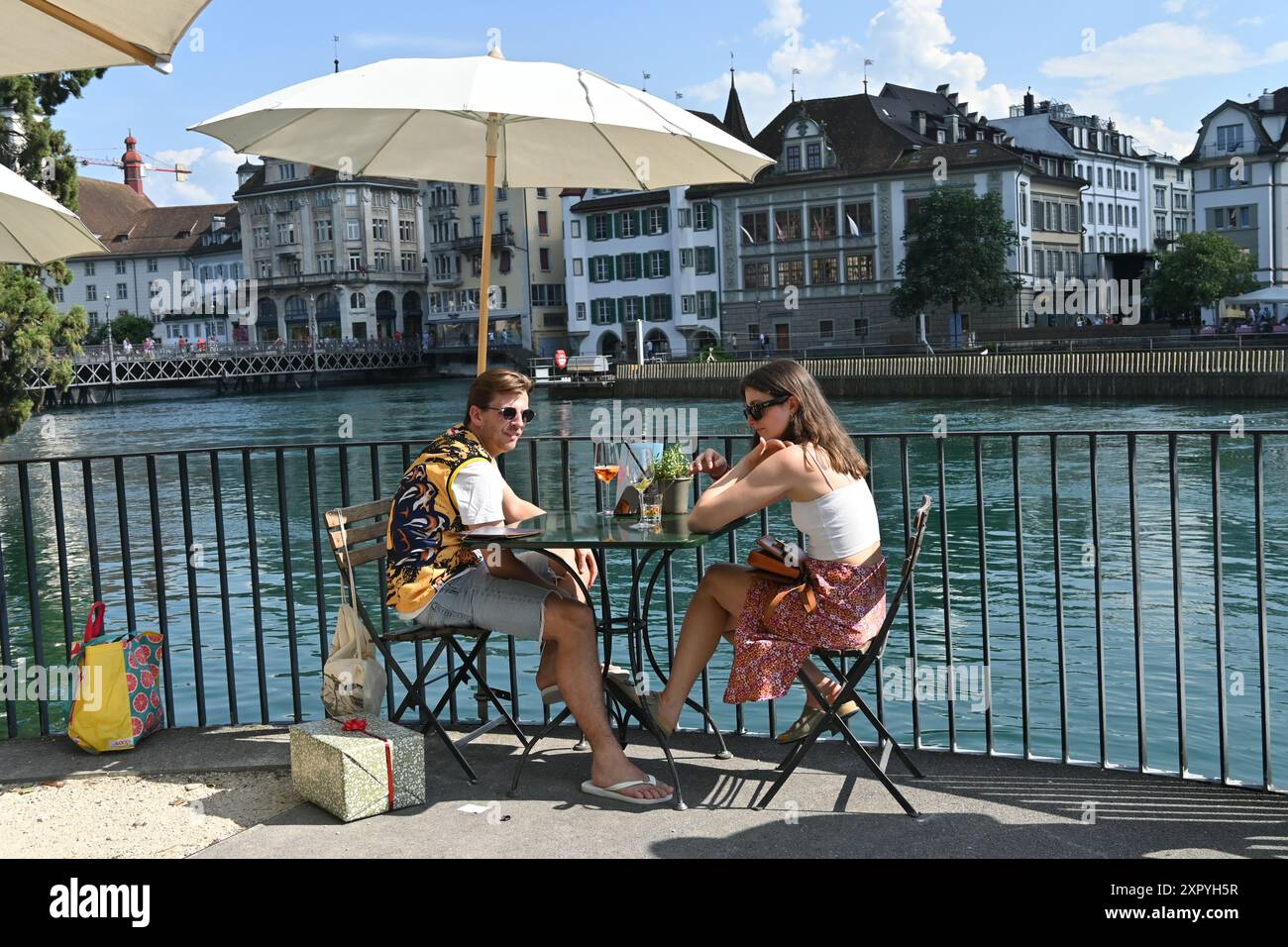 Tourists sitting outdoor in a bar facing river Reuss in Lucerne ...