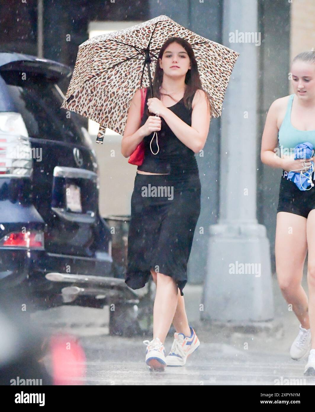Suri Cruise hides from the rain under an umbrella as she goes for a ...