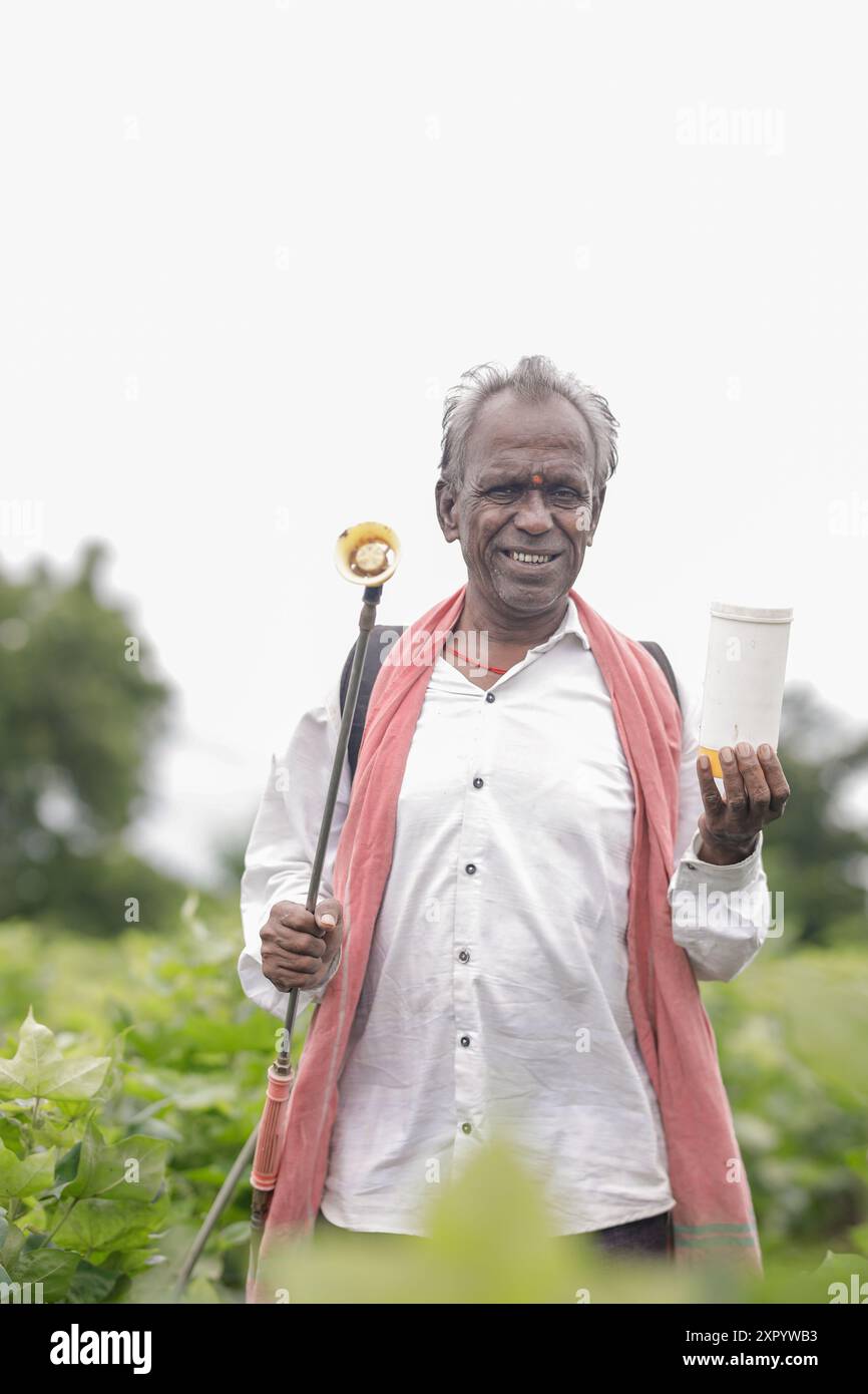 Indian farmer working on farm field, spraying fertilizer on soil and ...