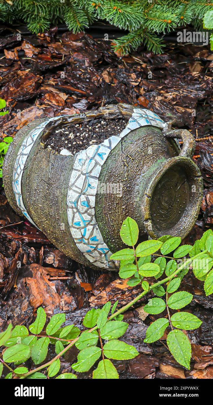 Decorative jug in the garden near flowers and trees. Rainy weather ...